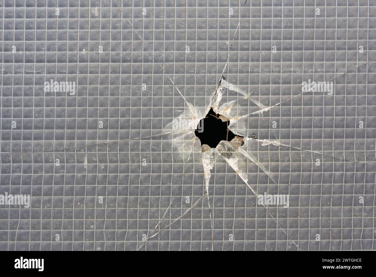 Hole in a destroyed safety glass window Stock Photo - Alamy