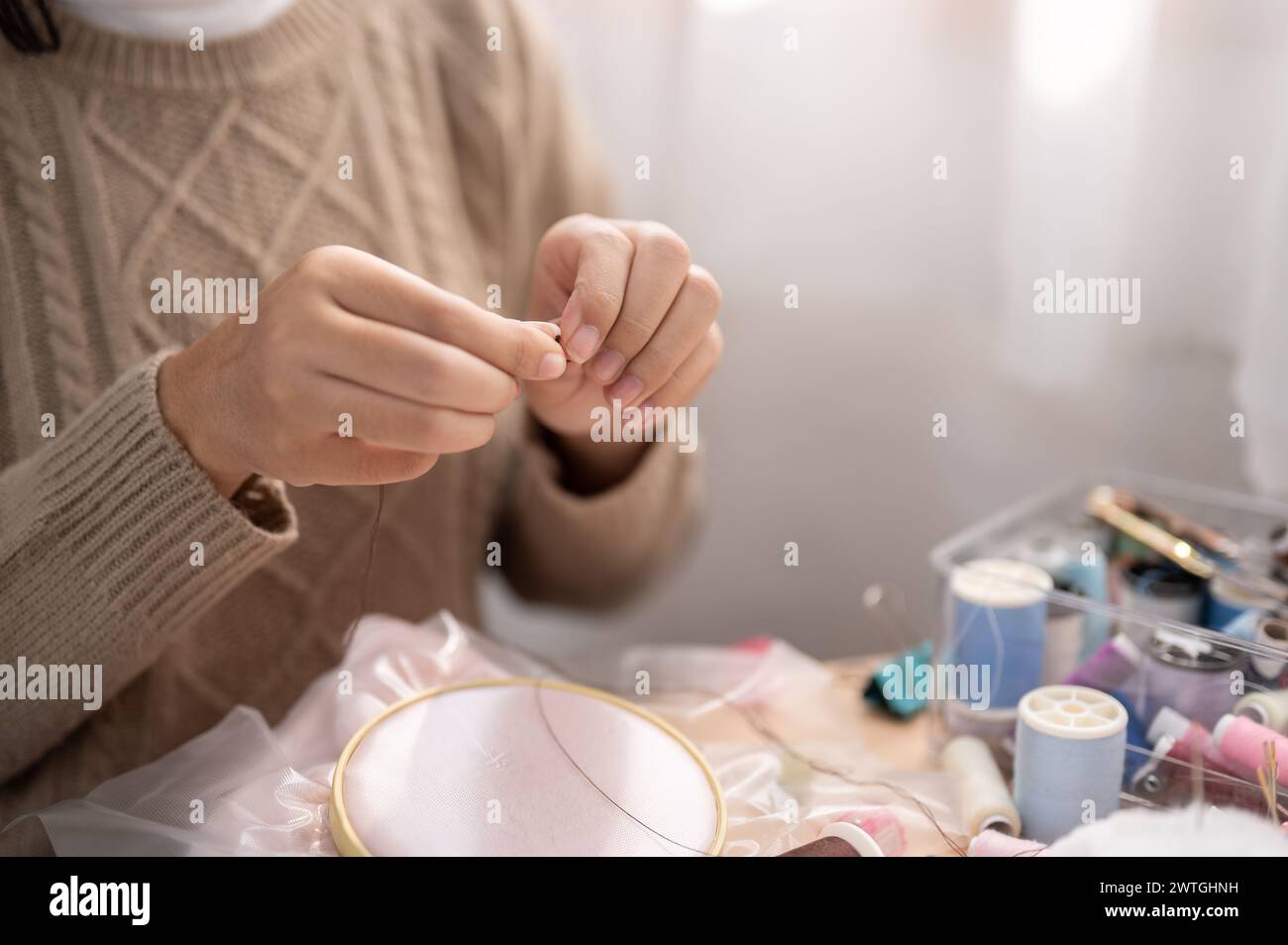 A close-up image of a woman inserting a needle, threading a sewing ...