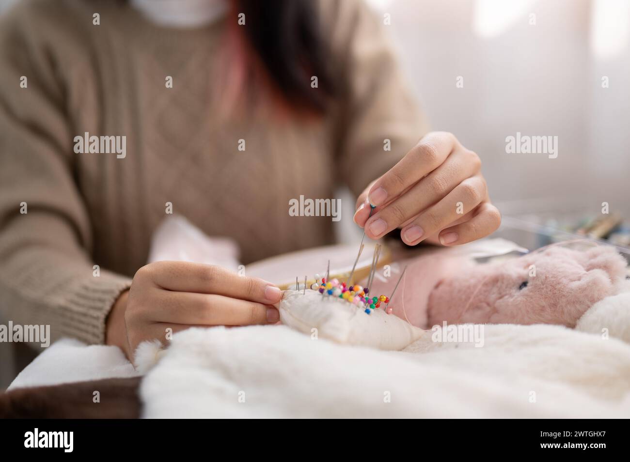 A close-up image of a woman pinning a pin on a pin cushion, stitching ...