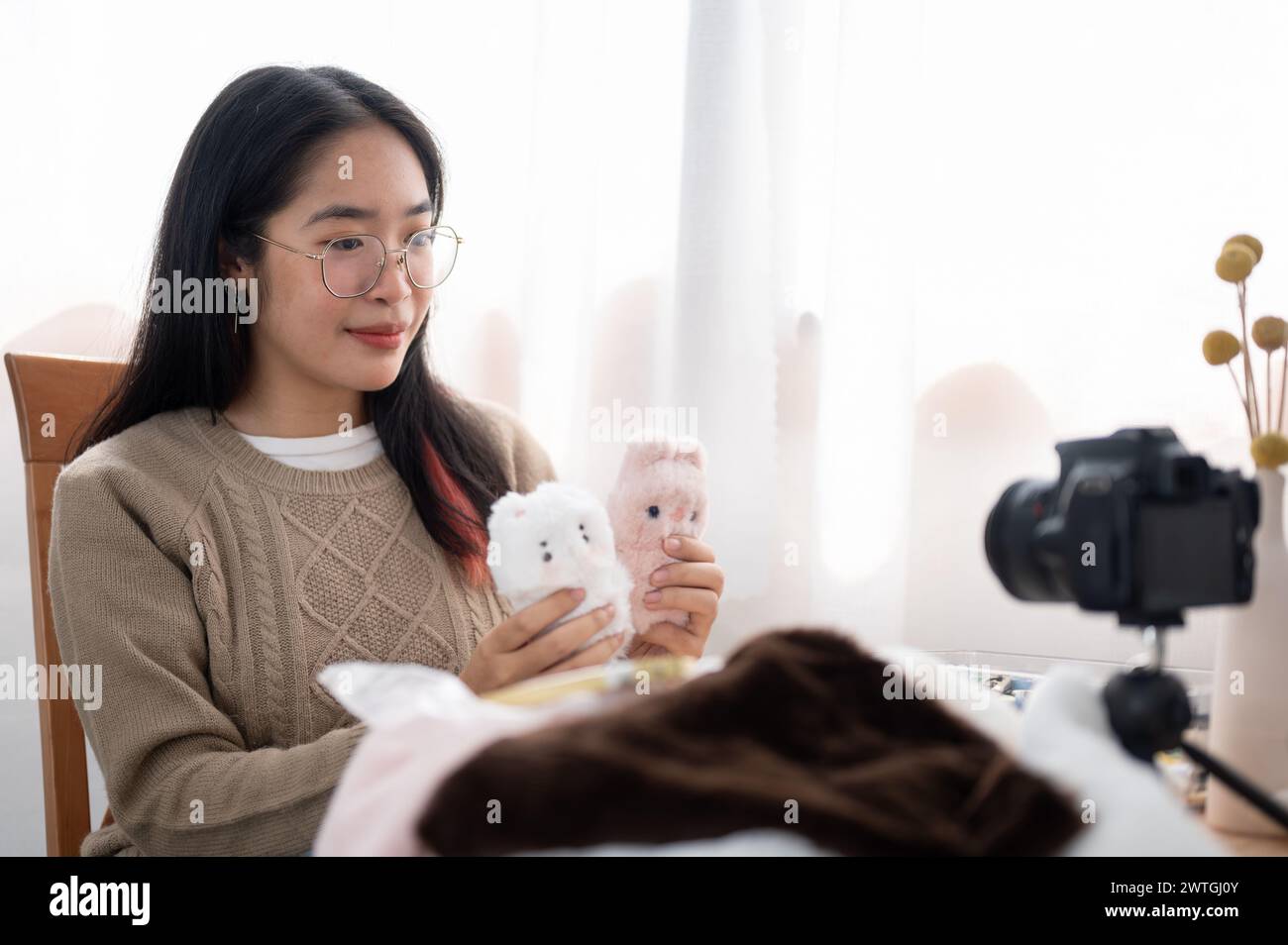 A cheerful young Asian female content creator showing her cute handmade ...