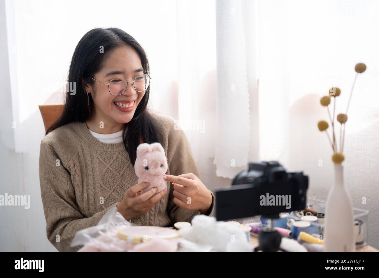 A smiling, cheerful young Asian female content creator is talking with ...