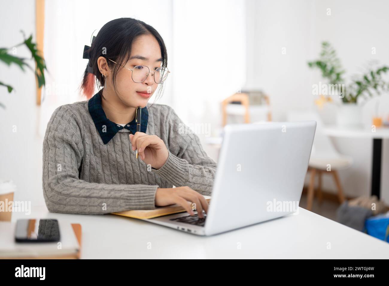 A beautiful young Asian female college student in a grey sweater and ...