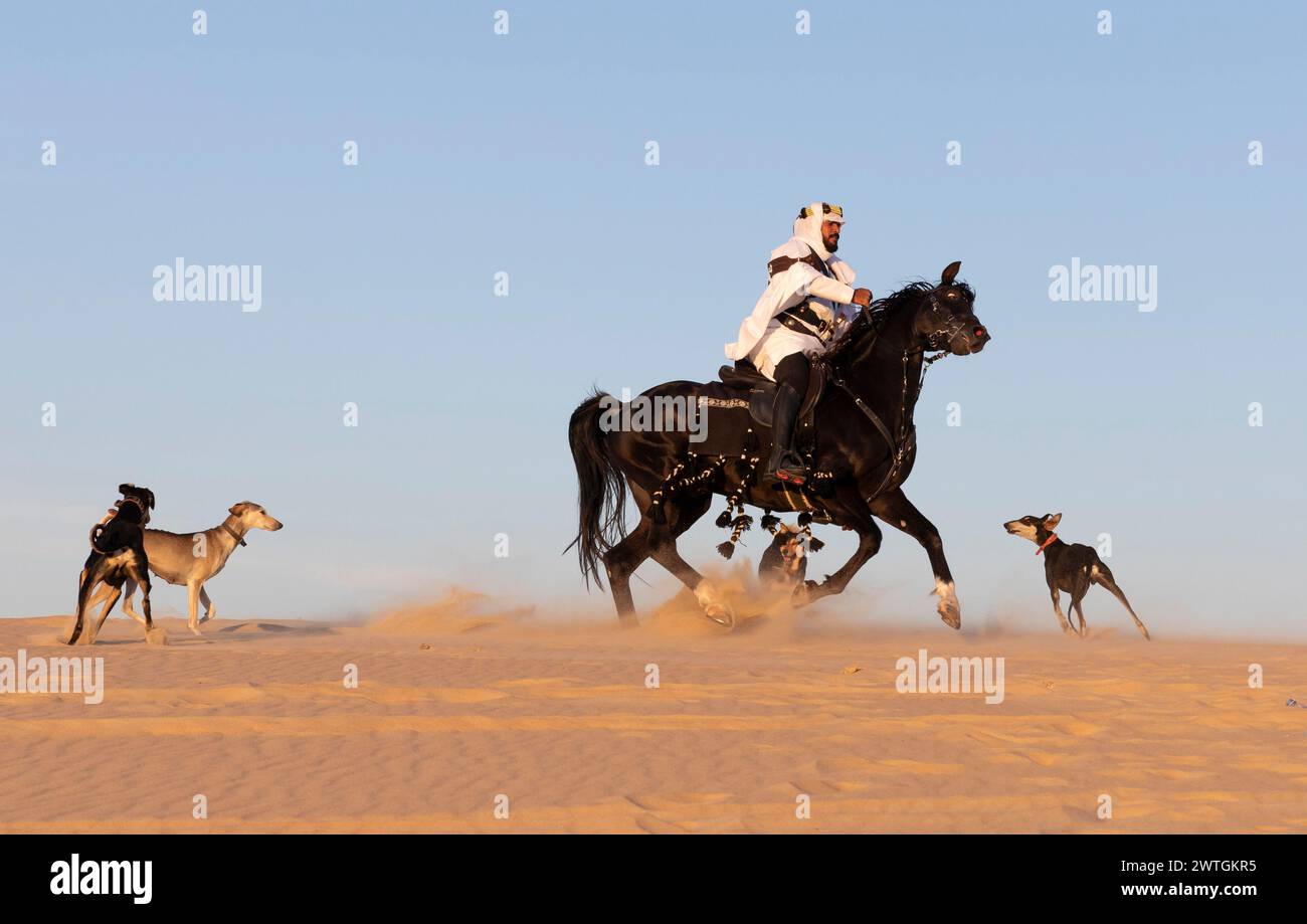 Man in traditional Saudi Arabian clothing in a desert with a black ...