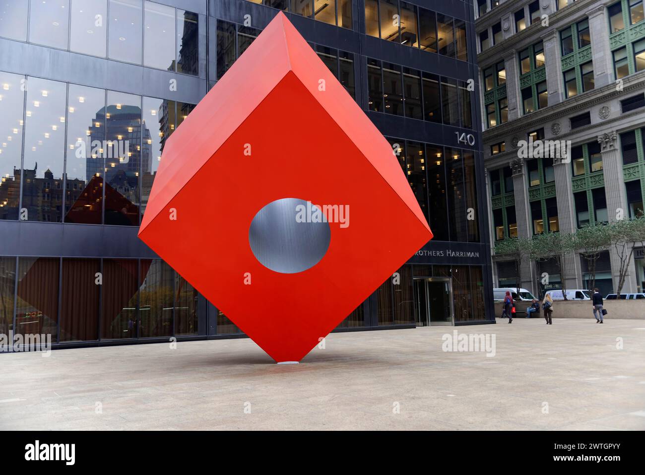 Red painted cubic sculpture with a circular hole in a public square ...