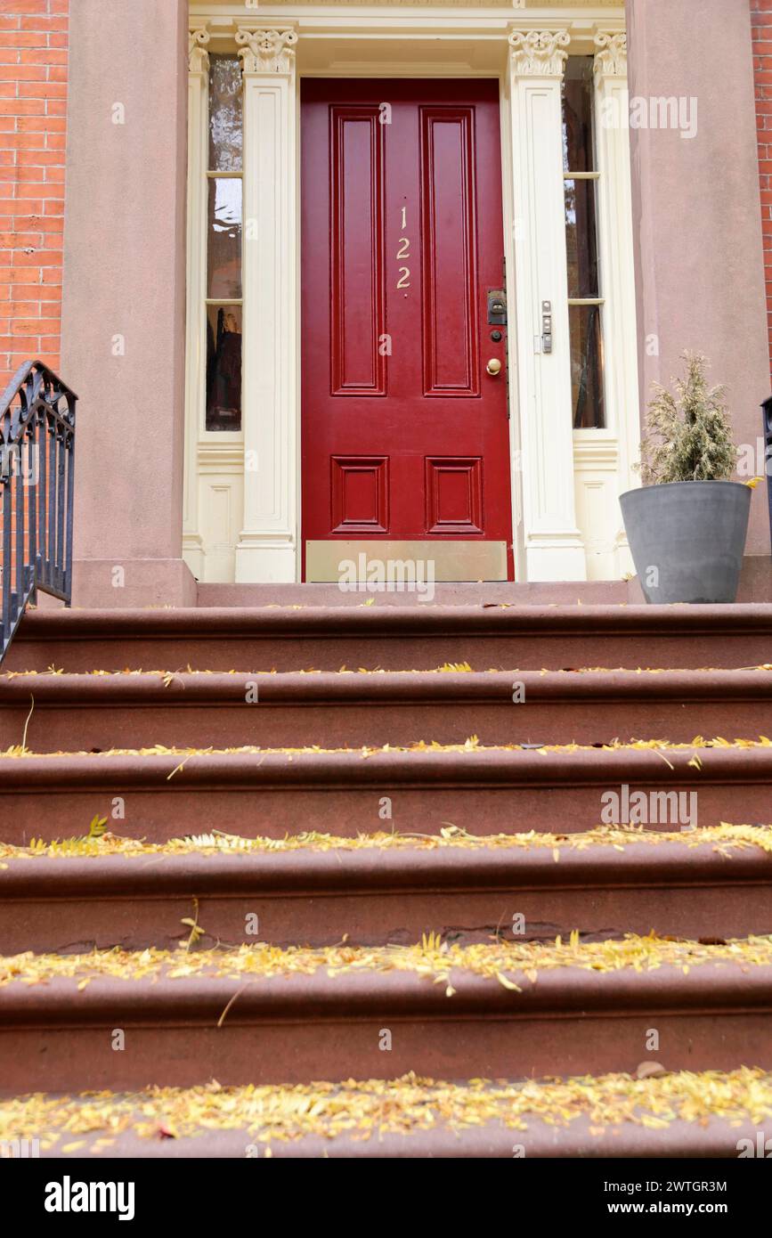 Red front door of a townhouse with steps and house number 122 ...