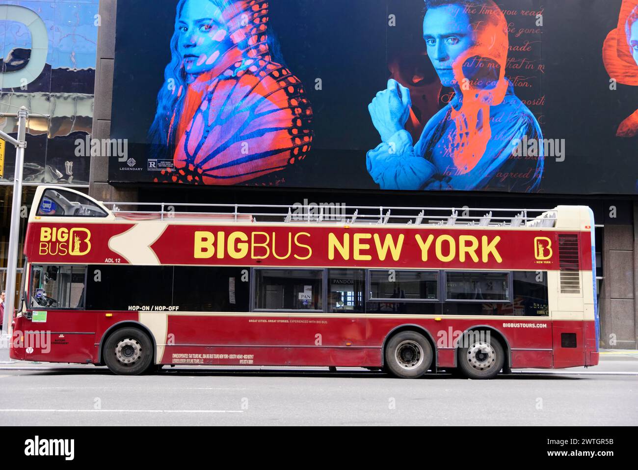 A red Big Bus New York double-decker bus in front of billboards ...