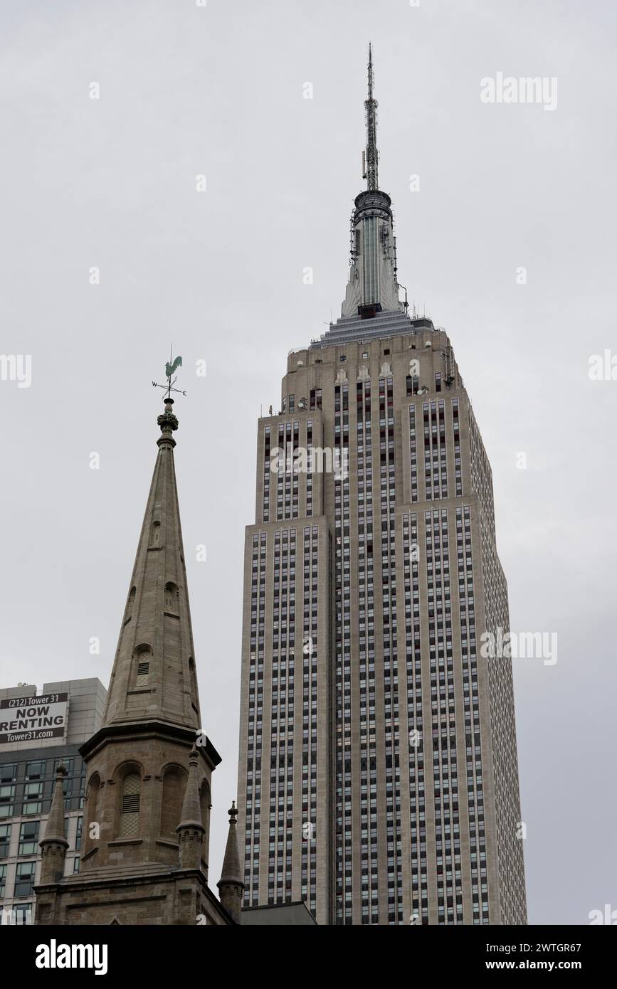 View of the Empire State Building next to a church spire, urban ...