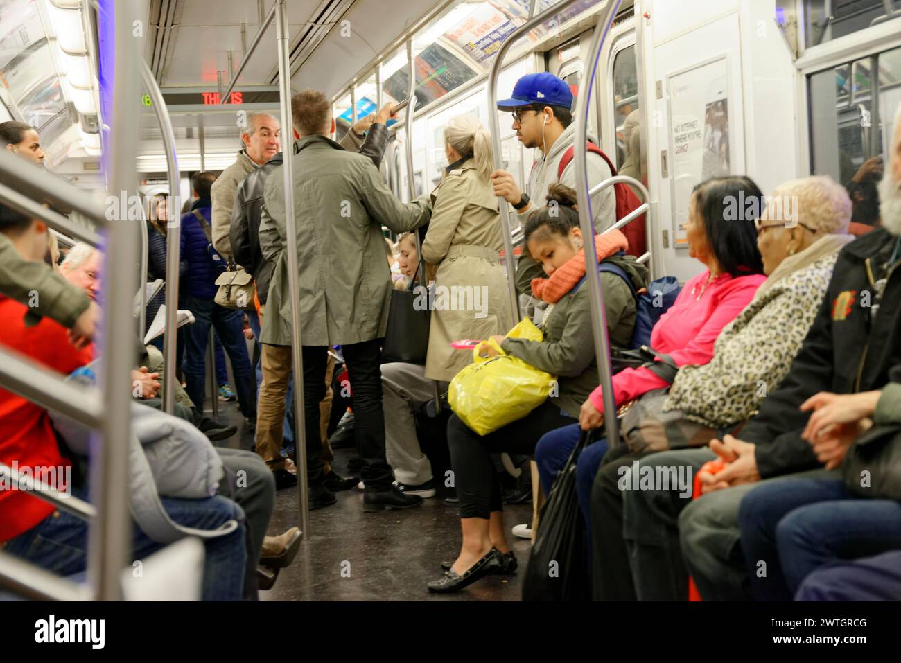 Passengers standing and sitting in a busy underground car, Manhattan ...