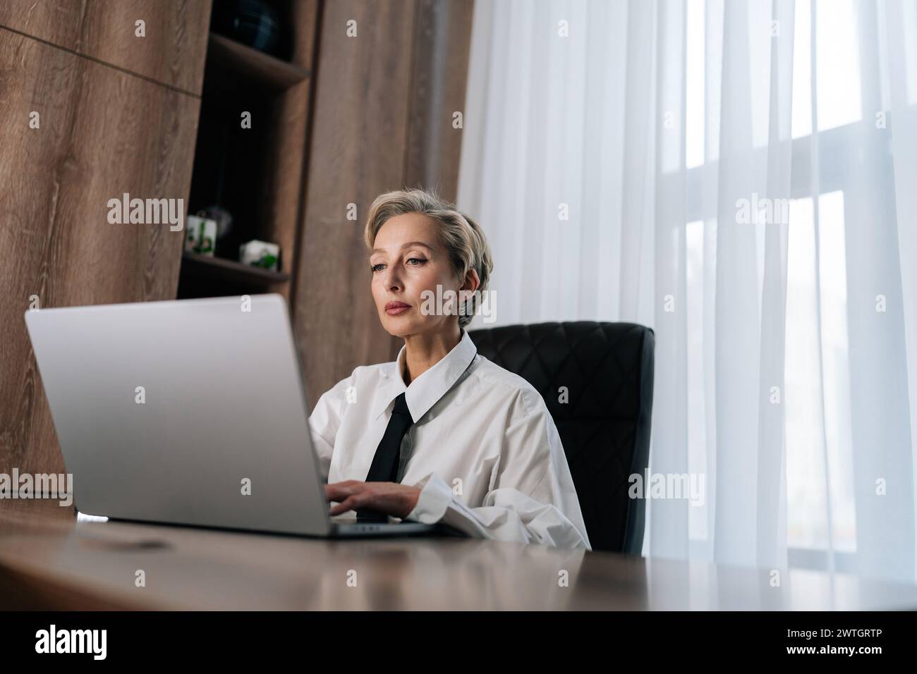 Shooting from below of concentrated middle-aged female entrepreneur ...