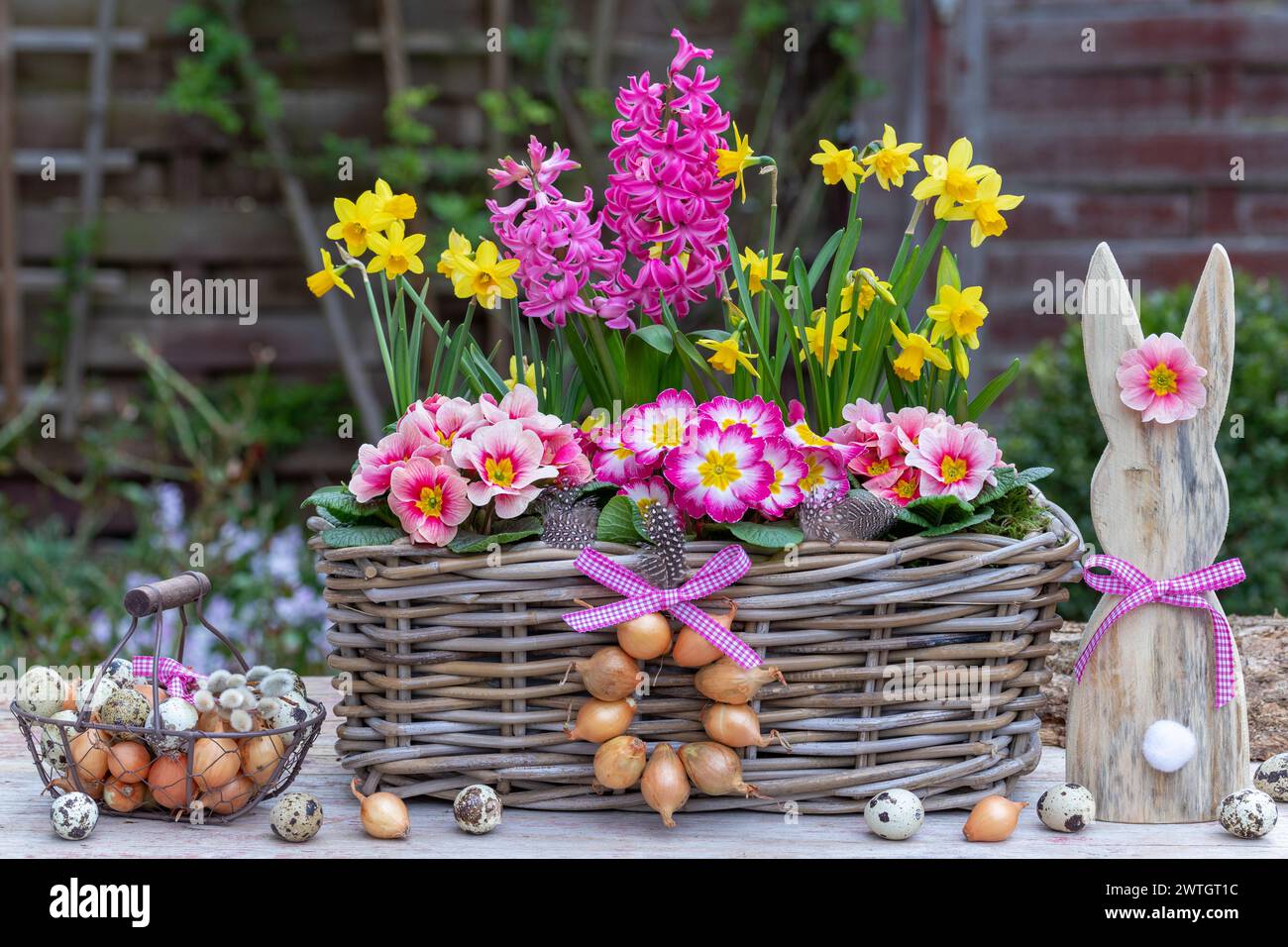 easter garden arrangement with easter bunny and spring flowers in pink and yellow in a basket ...