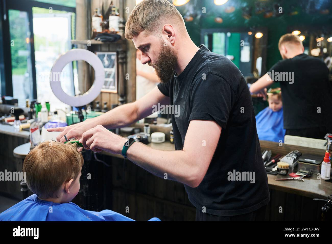 Professional hairdresser making haircut for his little client. Male ...