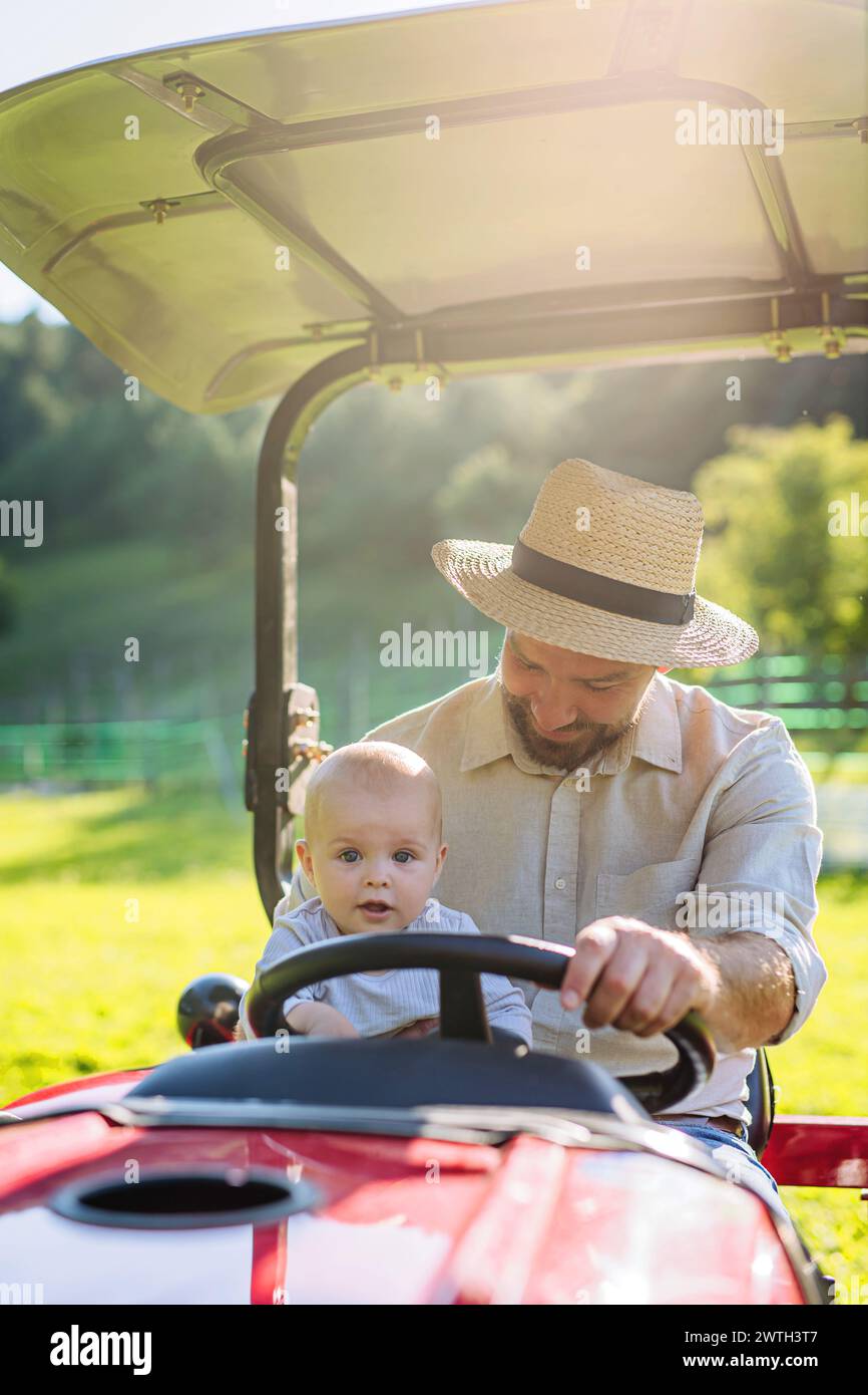 Farmer father riding tractor with his little baby son. Baby growing up ...