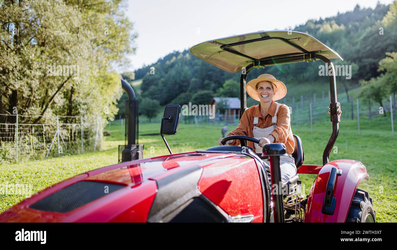 Progressive female farmer driving tractor on her own farm Stock Photo ...