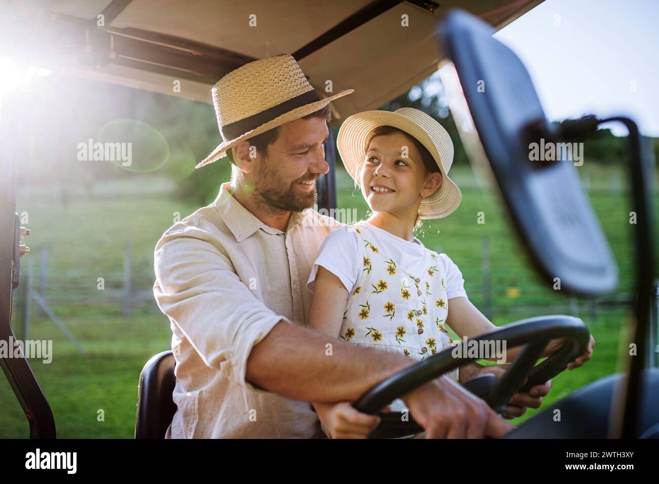 Farmer father riding tractor with his daughter. Girl growing up on ...