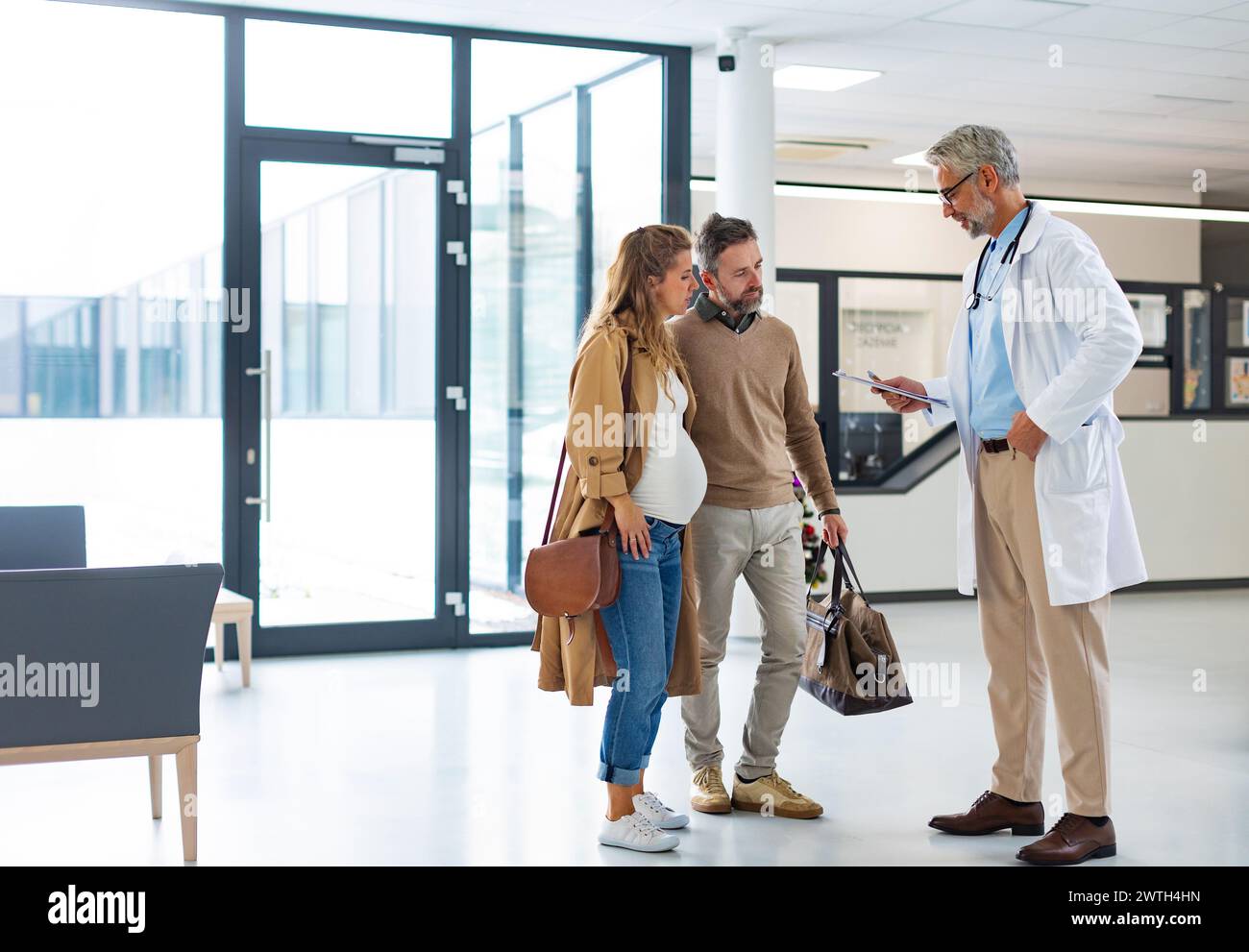 Pregnant woman and husband talking to obstetrician in hospital ...