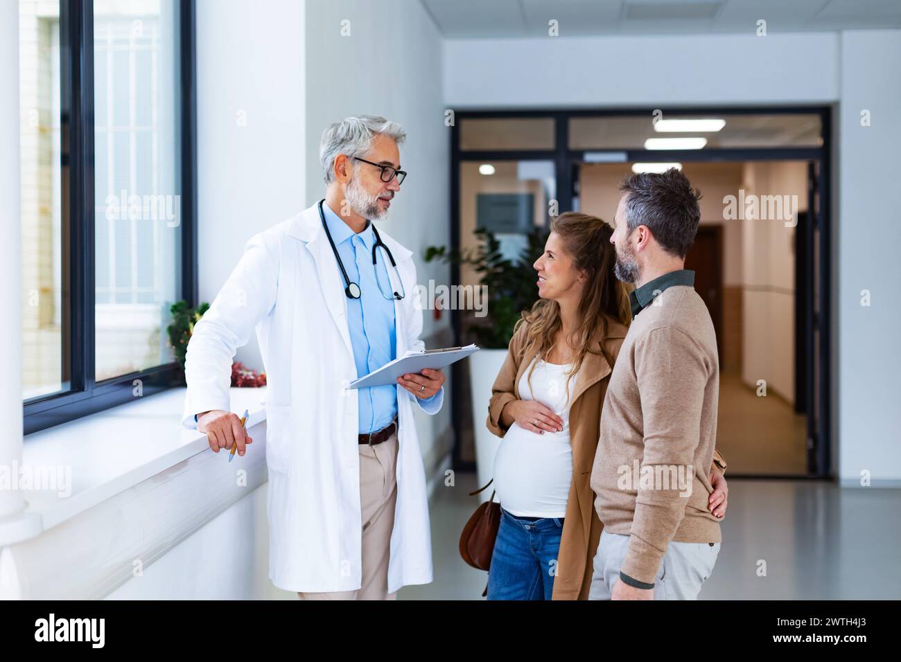 Pregnant woman and husband talking to obstetrician in hospital ...