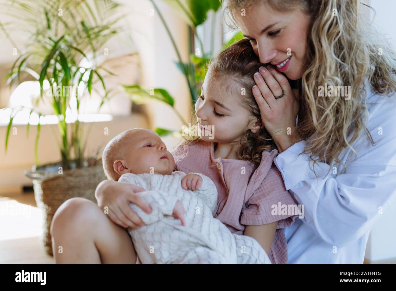 Girl hodling little baby, mother looking. Big sister meeting newborn ...
