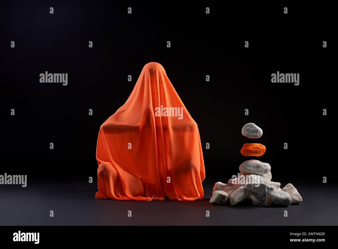 Unrecognizable woman under fabric levitate stones in black studio Stock ...