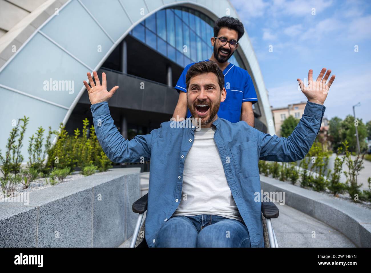Young smiling bearded man in wheelchair having a walk with a nurse ...