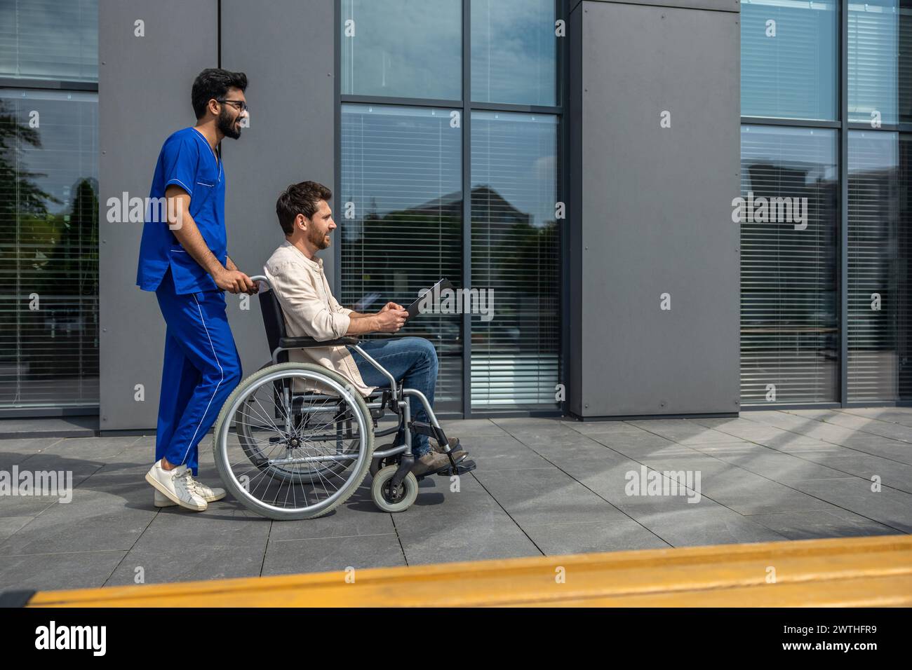 Tall bearded male nurse carrying the patient on a wheelchair Stock ...