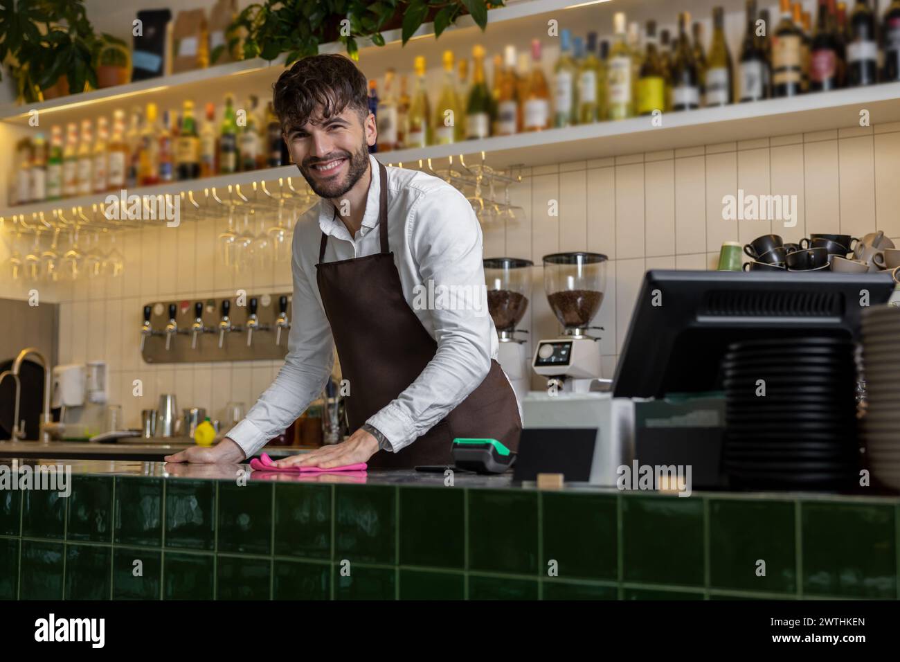 Handsome man bartender wiping bar counter in coffee house Stock Photo ...