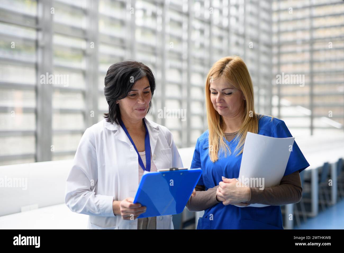 Two female doctors discussing test results, patients diagnosis. walking ...