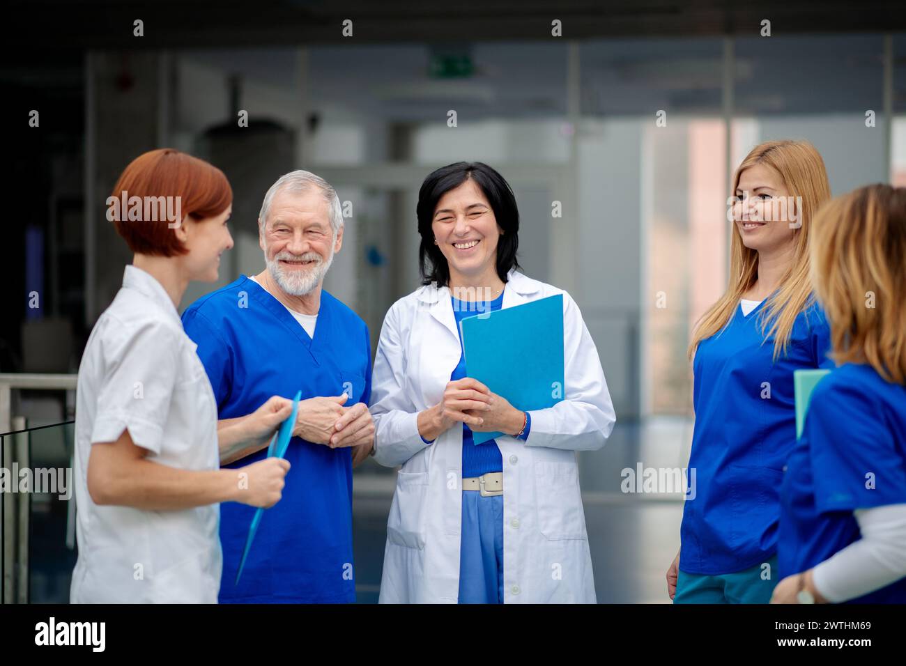 Team of doctors discussing unique medical case, walking across corridor ...