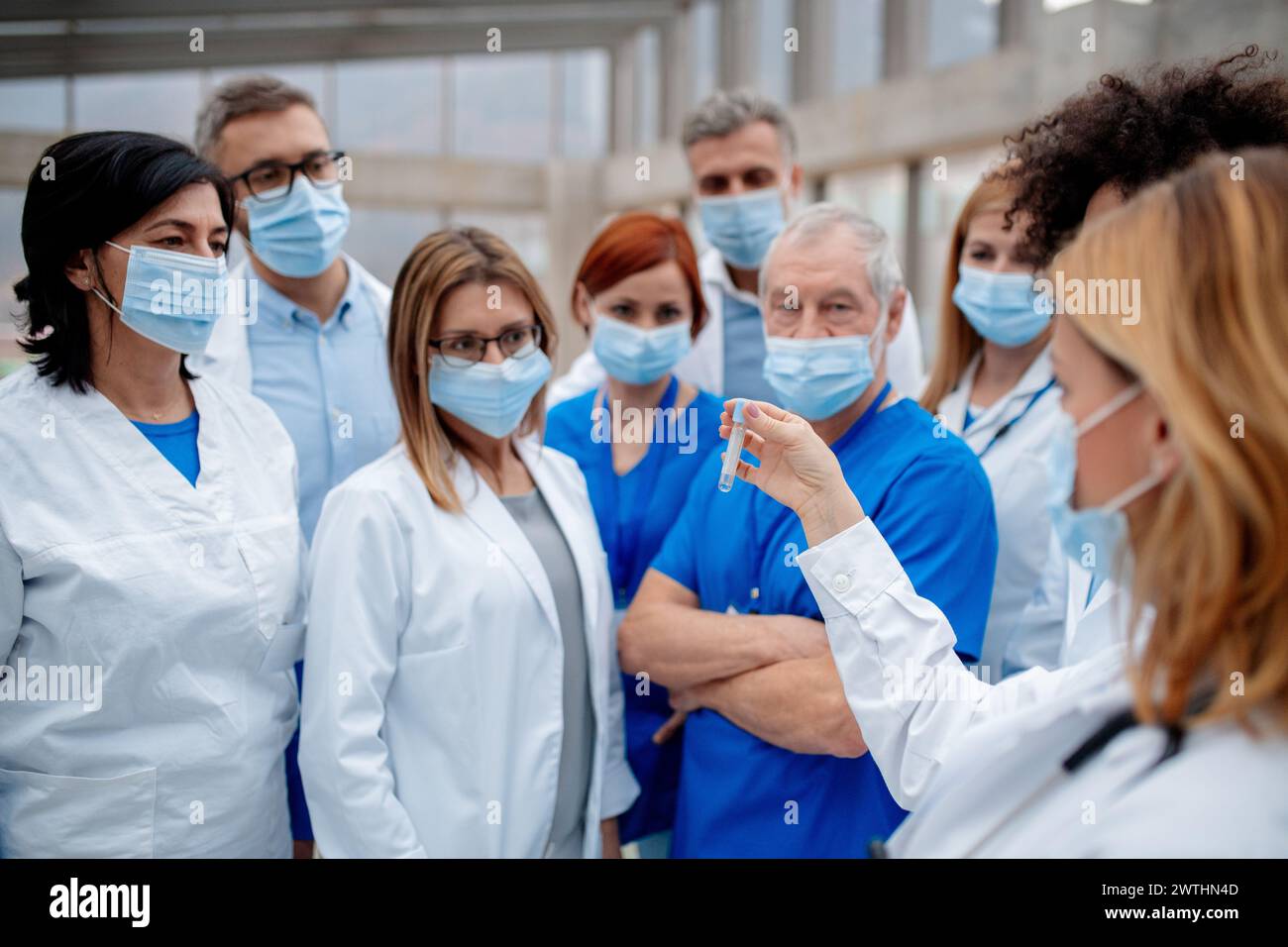 Healthcare team with surgical masks looking at ampule with dangerous ...