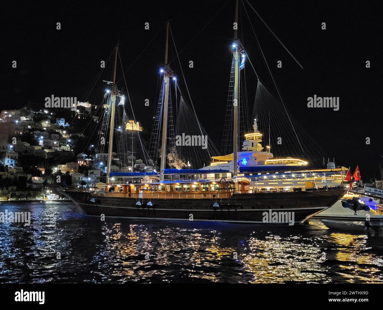 Greece, Island of Symi: Turkish sailing boat, "Bahriyeli C" at night in the brightly-lit harbour ...