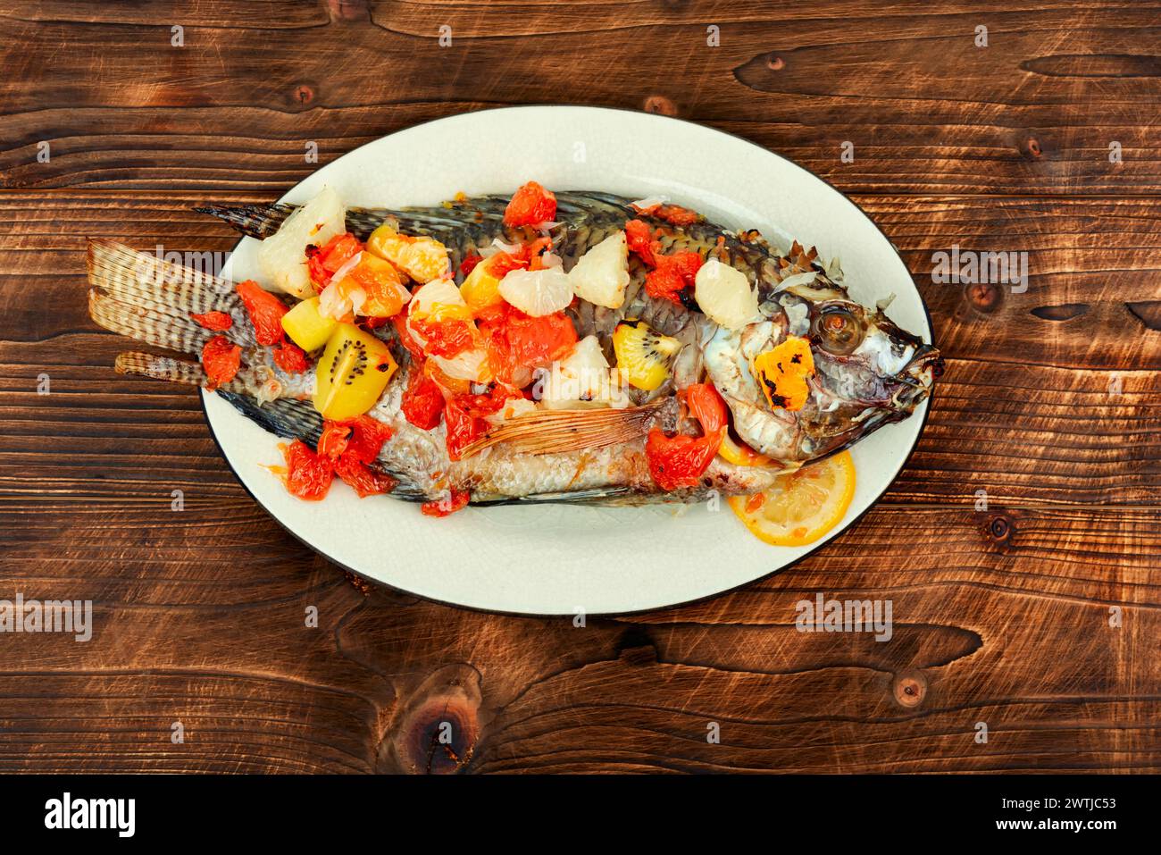 Delicious fried tilapia fish with fruit sauce in white plate. Pla Pao ...
