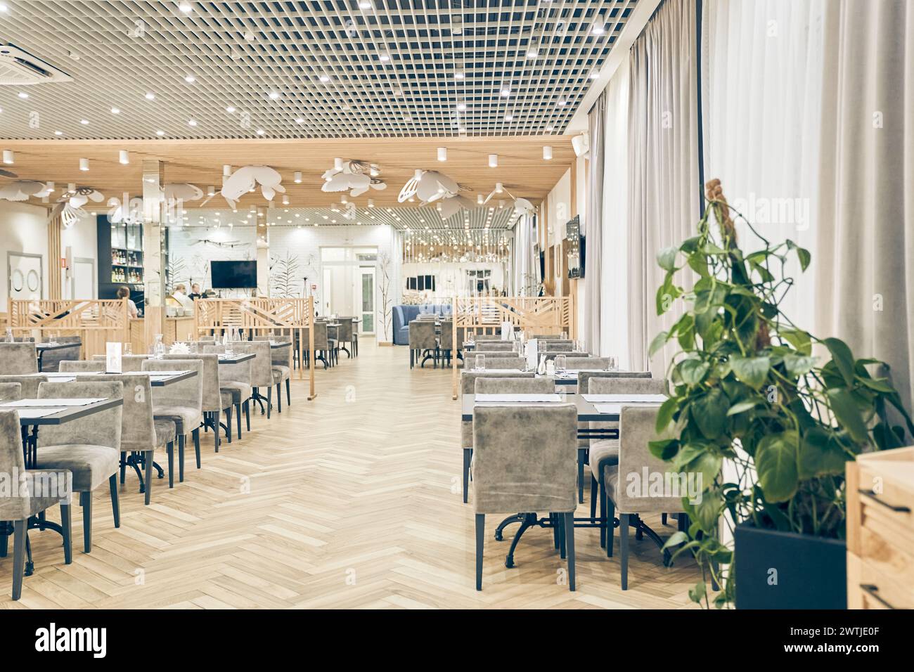 Side view of a large empty restaurant with tables, soft chairs ...