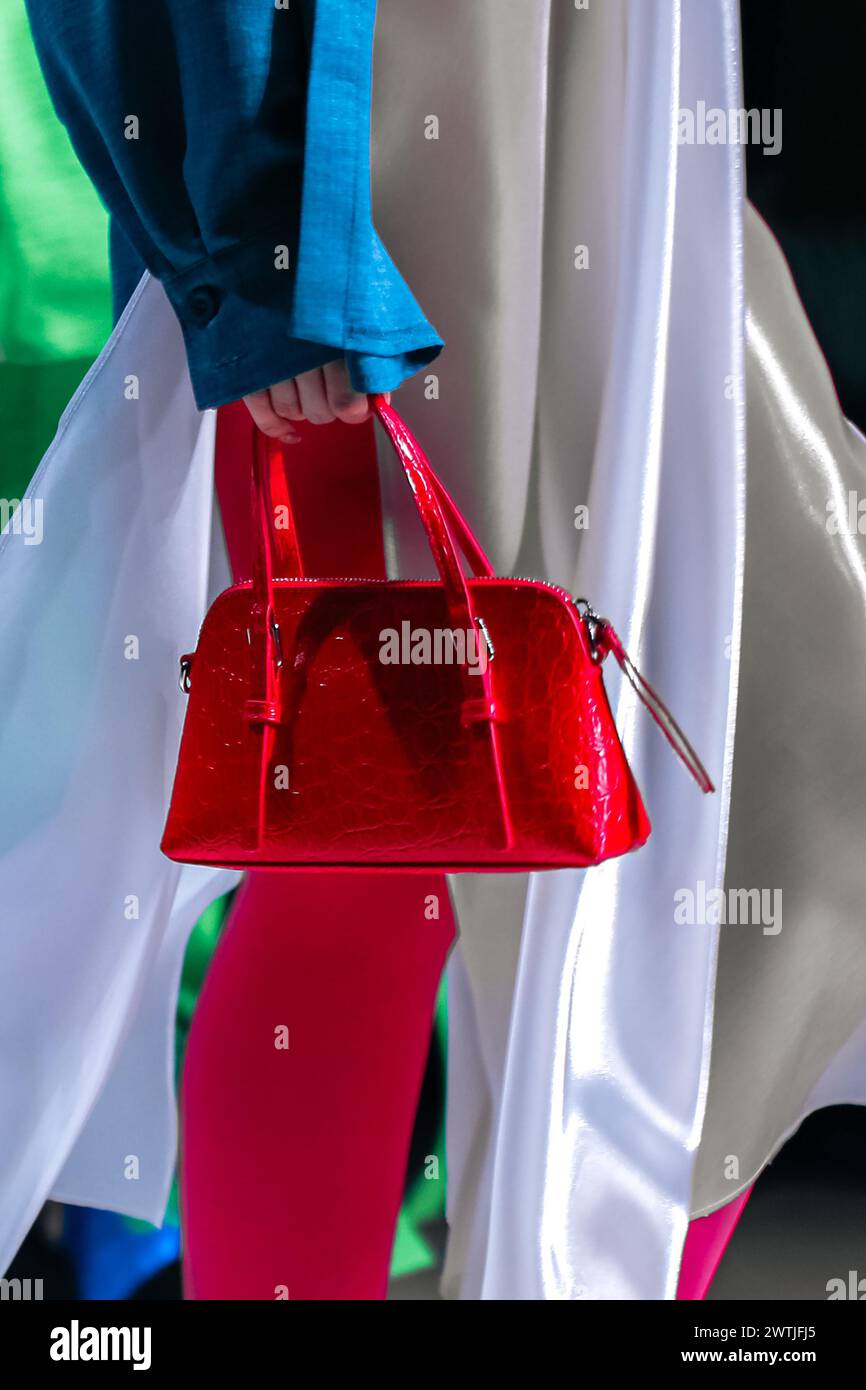 White silk long dress and small red handbag in a woman's hand. Elegant ...
