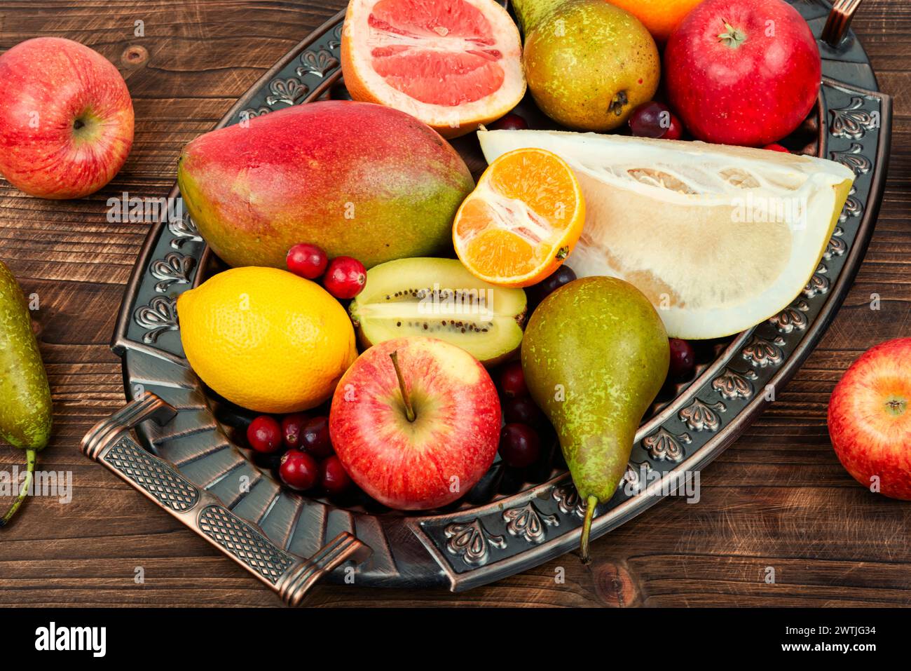 Apples, pears, mangoes and citrus fruits on a stylish tray. Still life ...