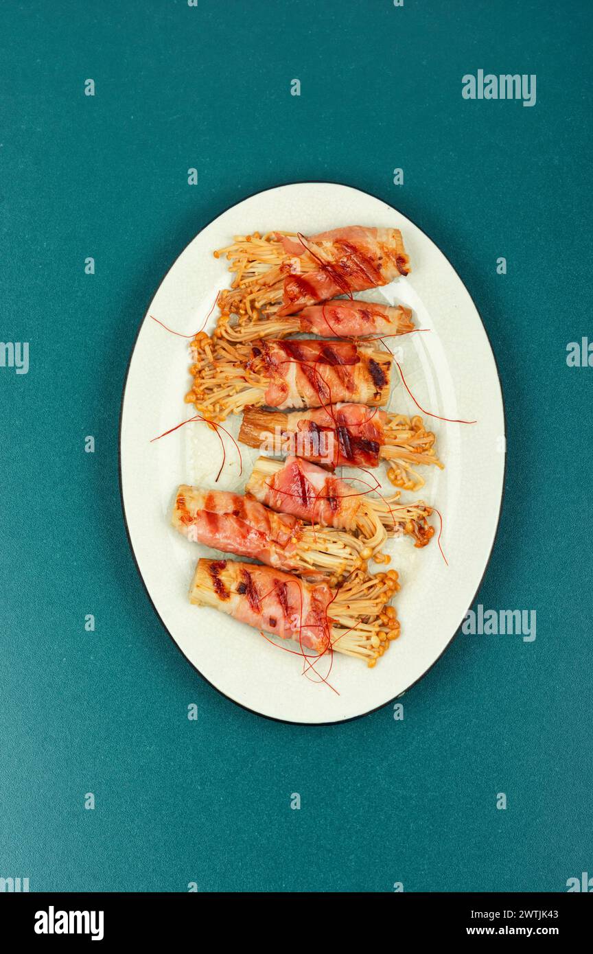 Enoki mushroom roll roasted in bacon on plate. Bacon wrapped mushroom ...