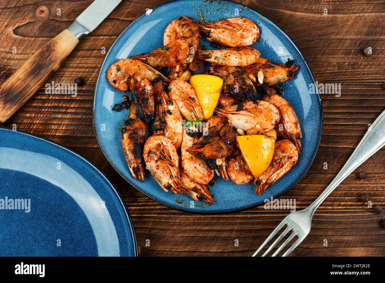 Roasted unpeeled shrimp on a plate. Dark rustic wooden background. Top ...