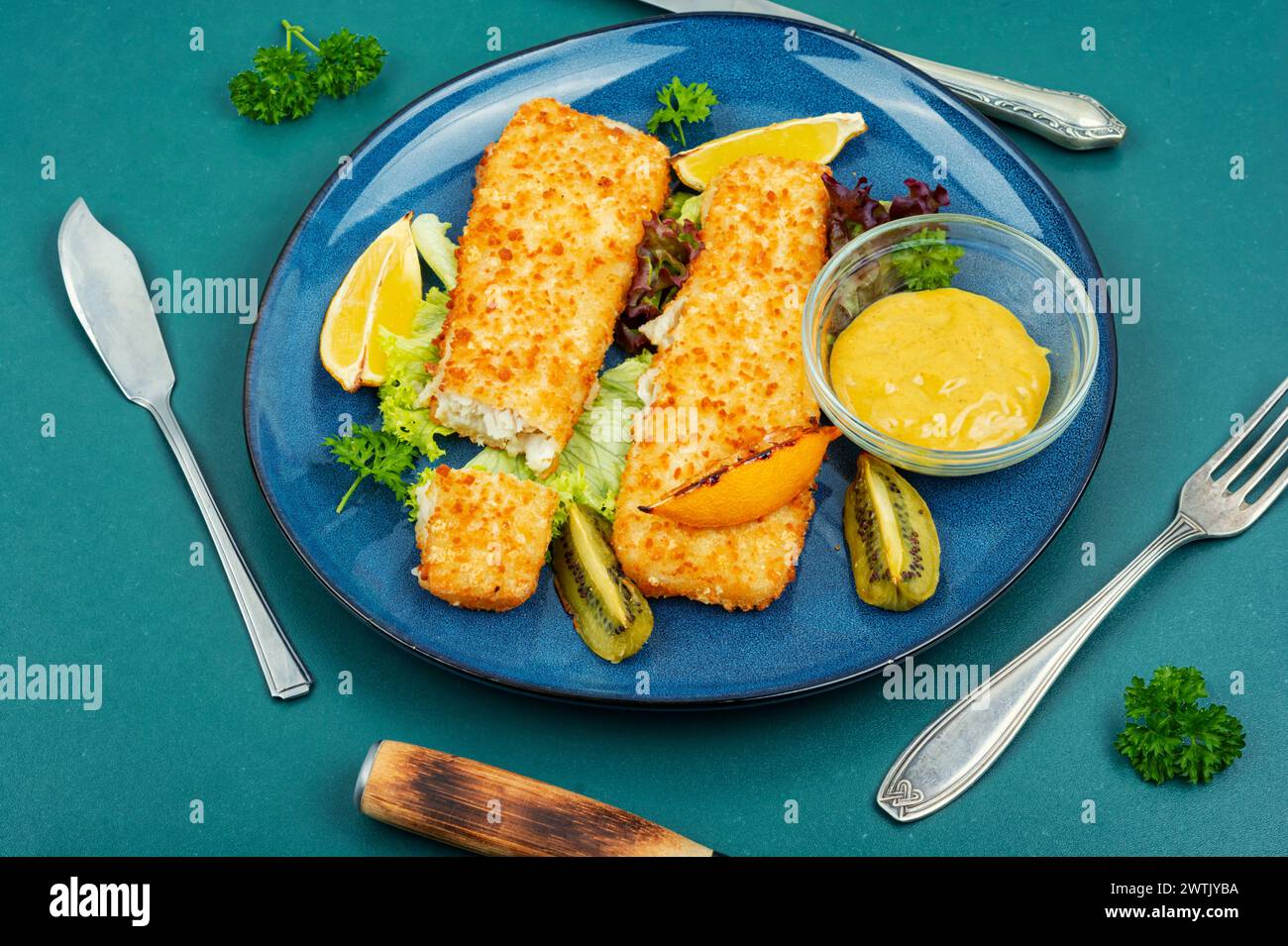 Pollock fillet roasted in bread crumbs served with sauce and kiwi. Fish ...