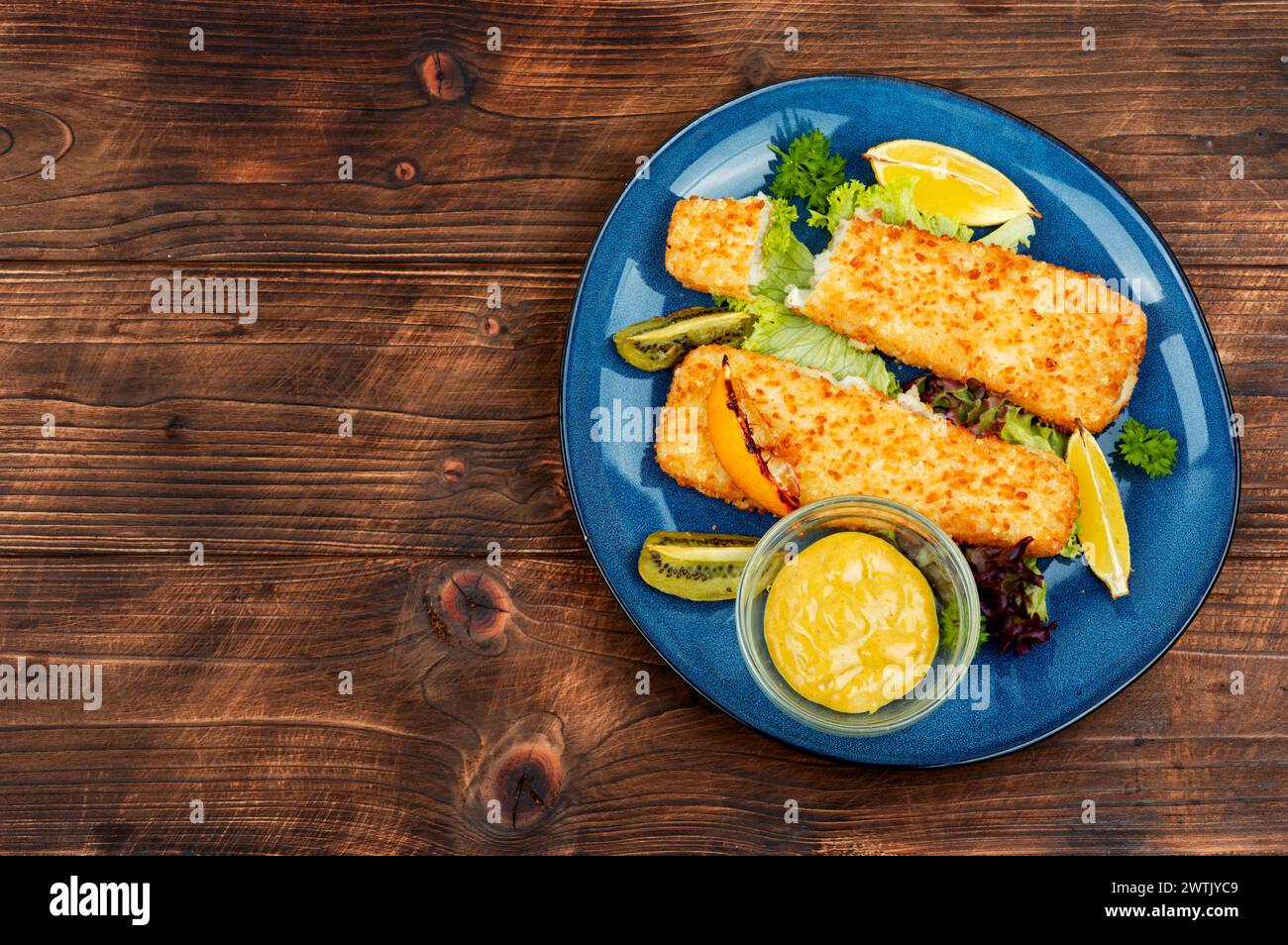 Pollock fillet roasted in bread crumbs served with sauce and kiwi. Fish ...