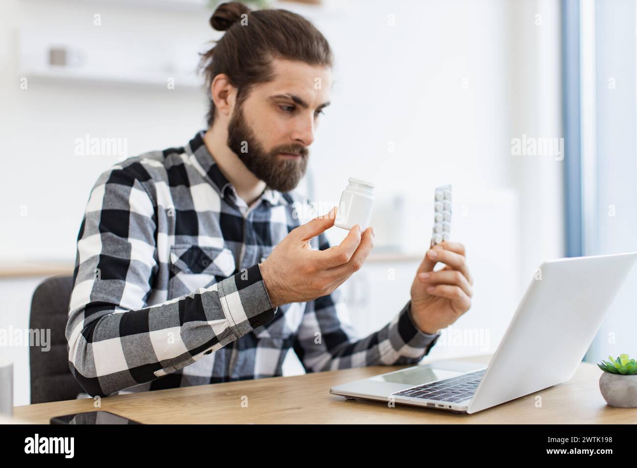 Medicine held by Caucasian young man looking through information on ...