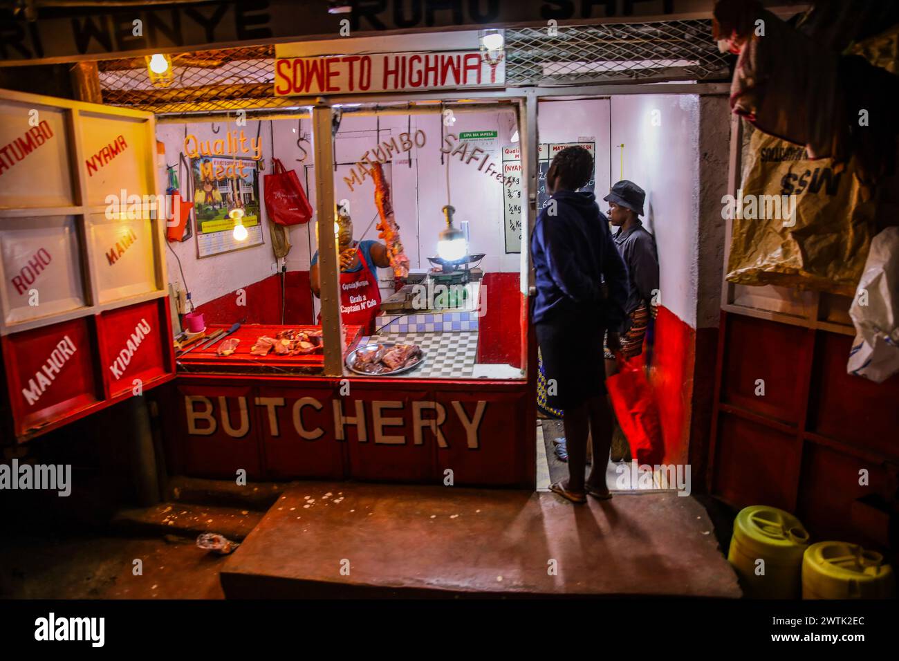 A woman waiting to be served outside a butcher in Kibera Slum, Nairobi ...