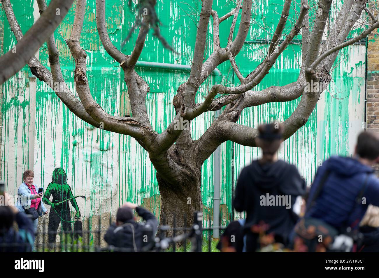 People look at a new Banksy painting on a wall in London, Monday, March ...