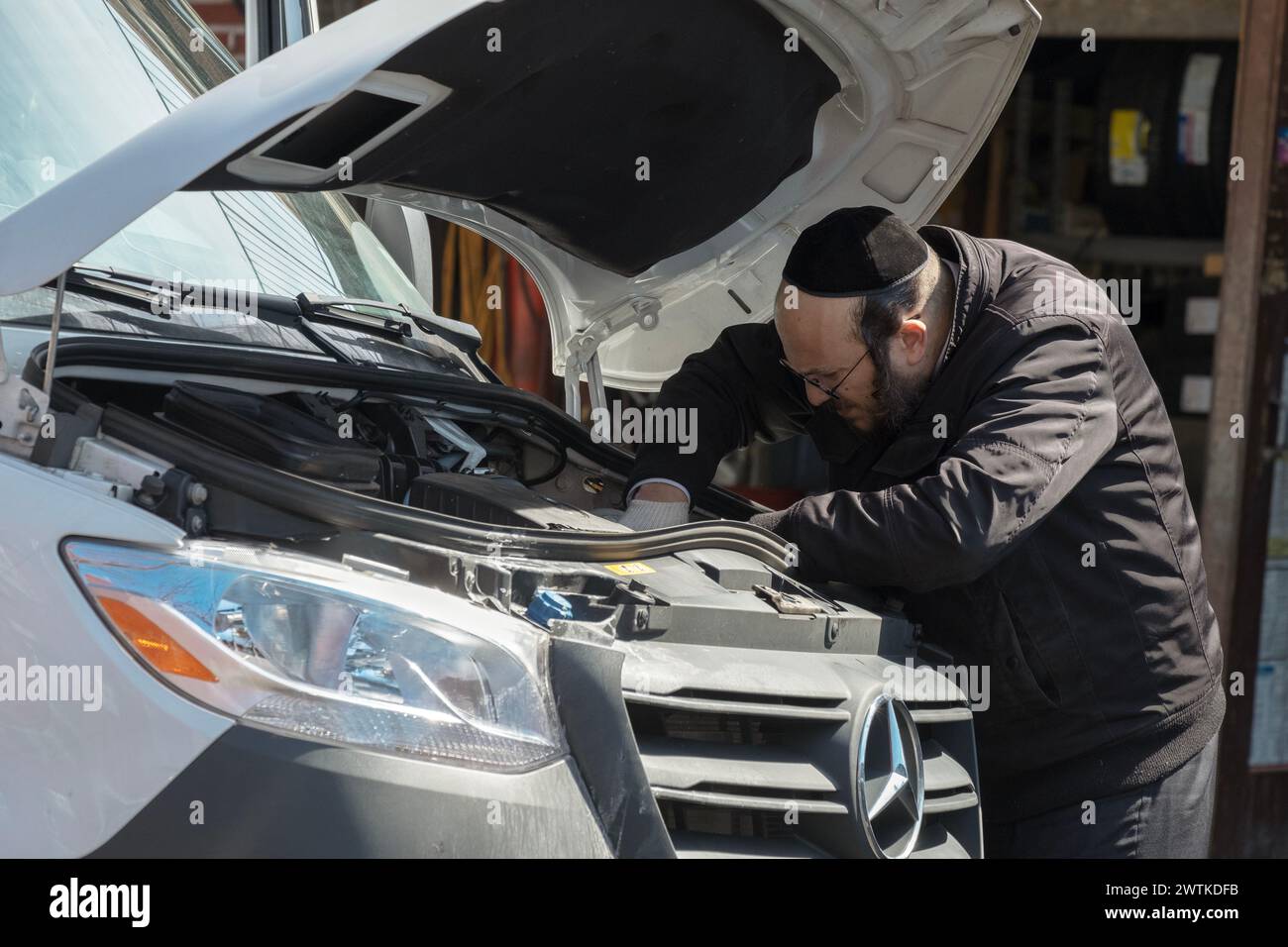 An orthodox Jewish man working on the engine of a Mercedes Benz SUV. In ...