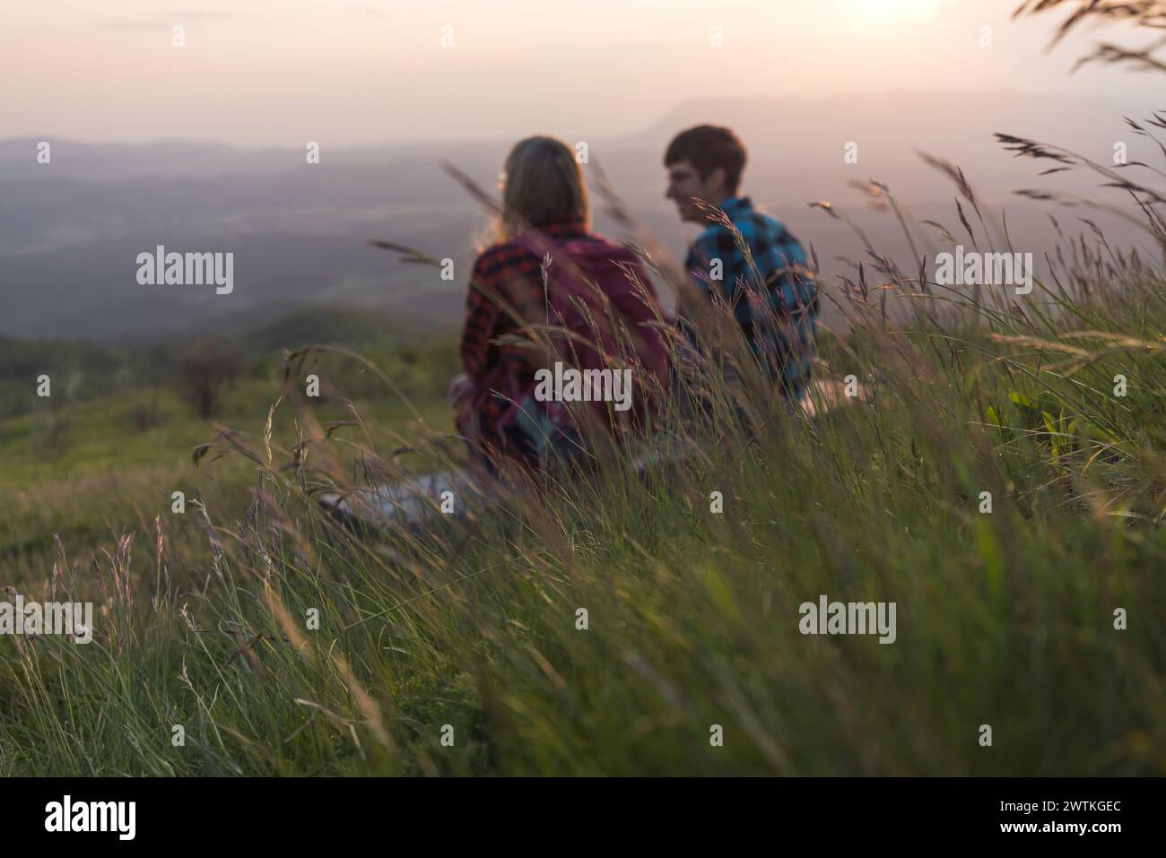 Young couple enjoying the fantastic mountain panorama at sunset while ...