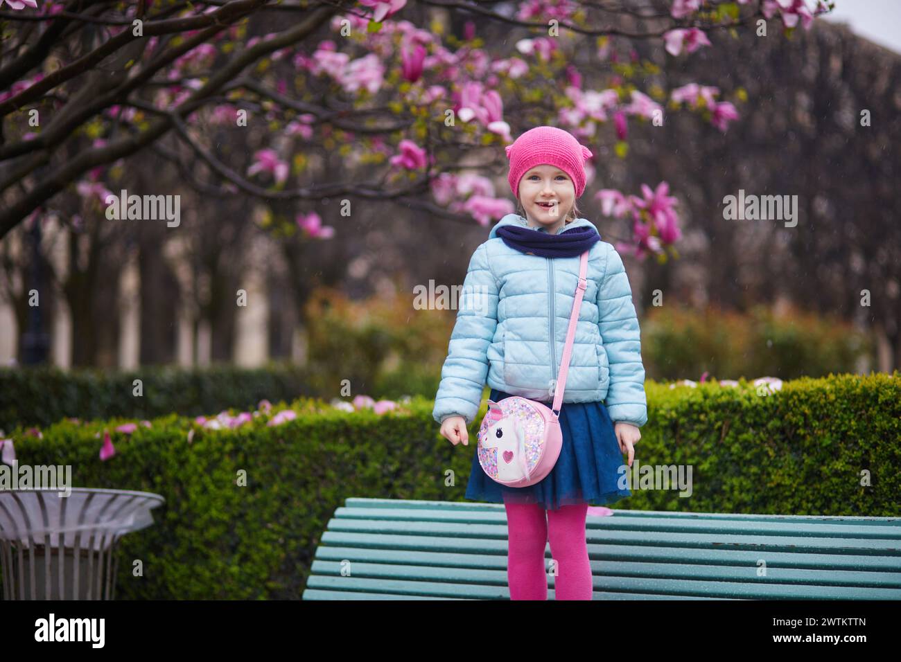 Adorable preschooler girl enjoying pink magnolias in full bloom on a ...