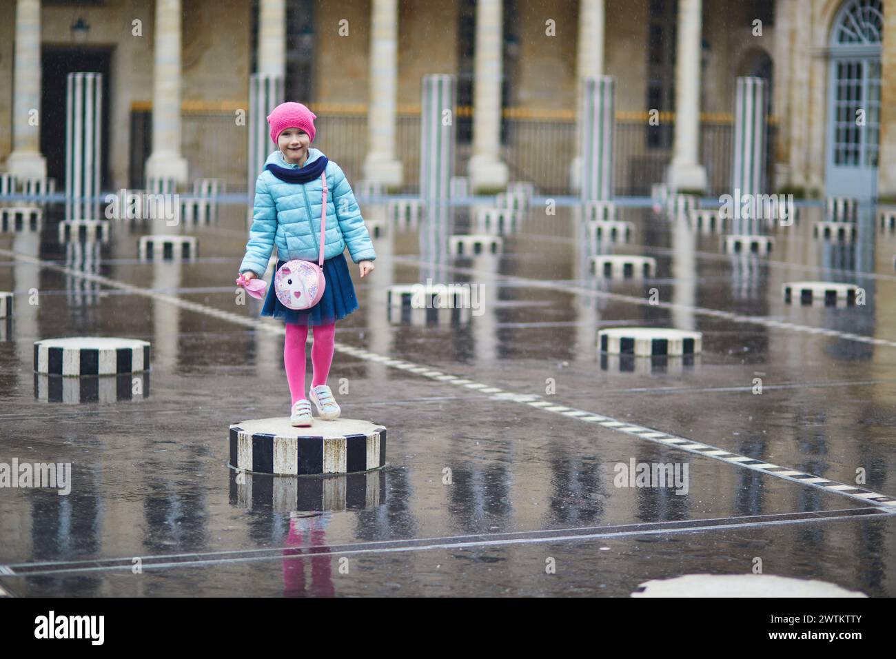 Adorable preschooler girl playing in Palais Royal garden on a rainy day ...