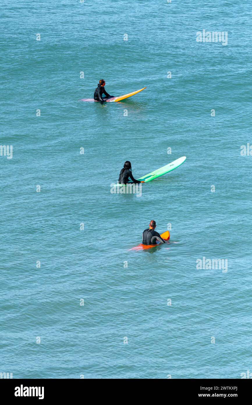 Surfers sitting on their surfboards floating in the sea waiting for a ...