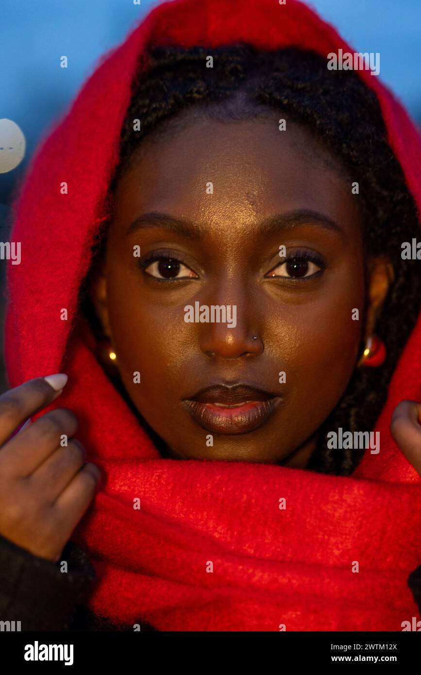 A captivating close-up portrays a woman pulling a vivid scarlet wrap ...