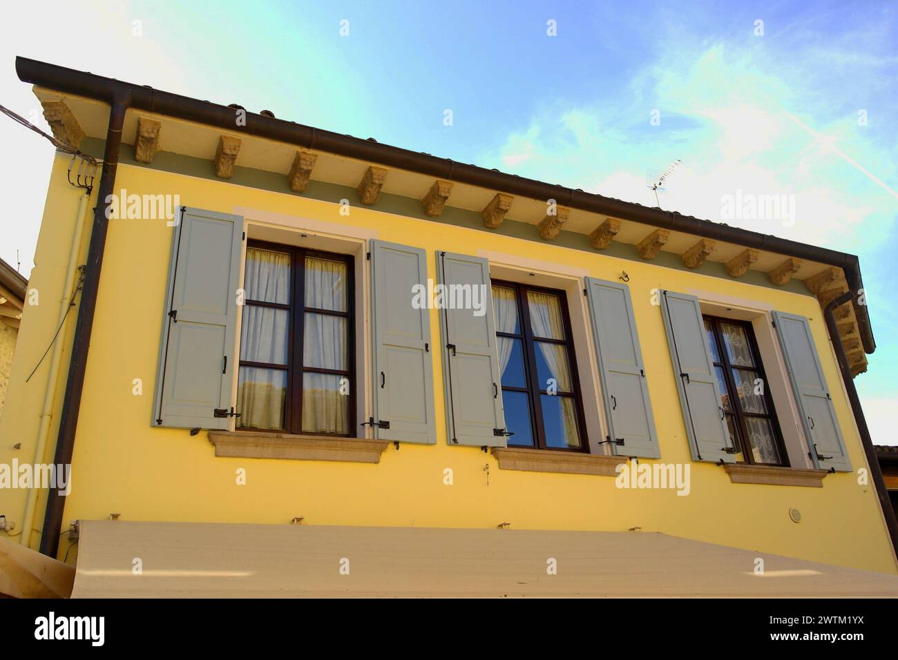 Side facade of a yellow house with three windows Stock Photo - Alamy