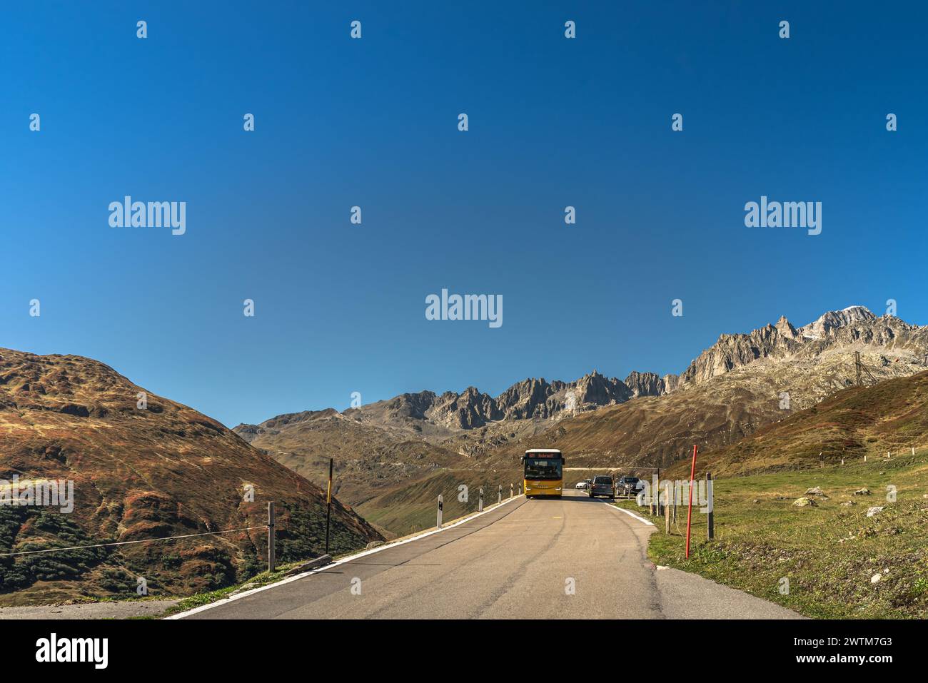 Mountain landscape at the Furka Pass, a yellow public bus drives on the ...