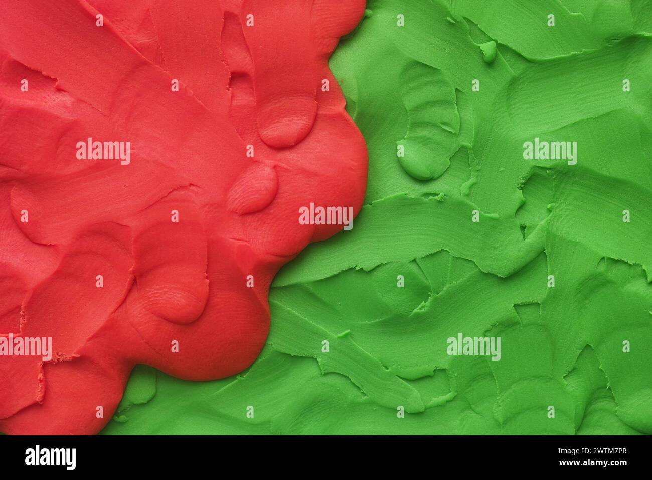 A background texture made out of red and green play clay. Close up ...