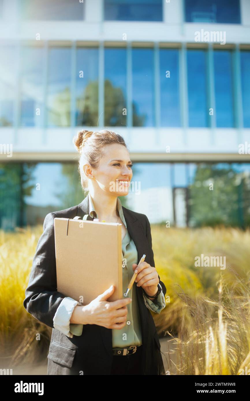 smiling modern female employee near business center in black jacket ...